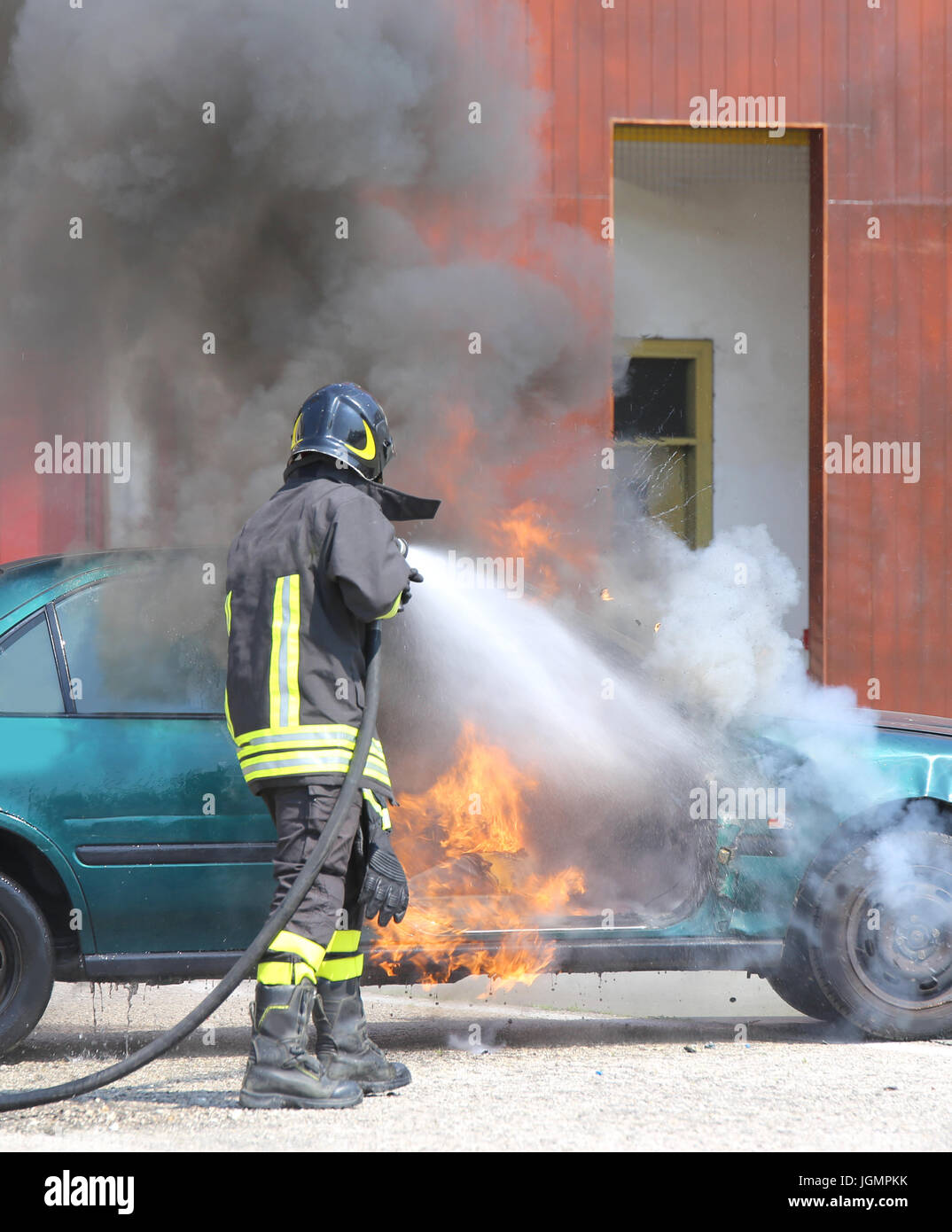 broken car with flames and black smoke and firefighter intervening to ...
