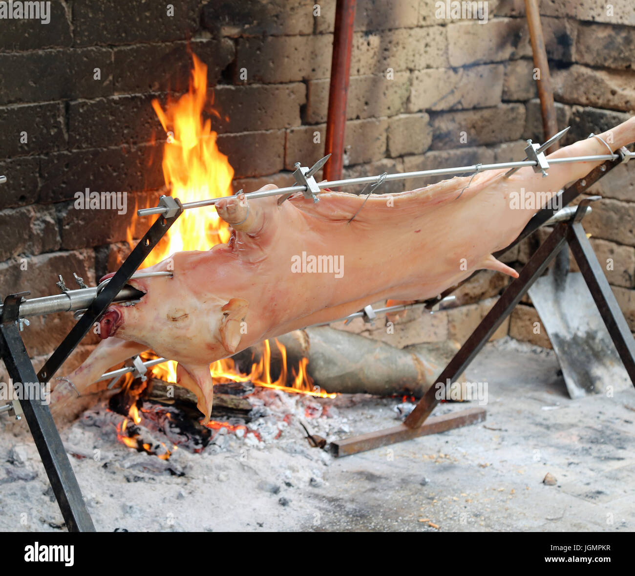 cooked whole pig on a spit with fire wood embers Stock Photo - Alamy
