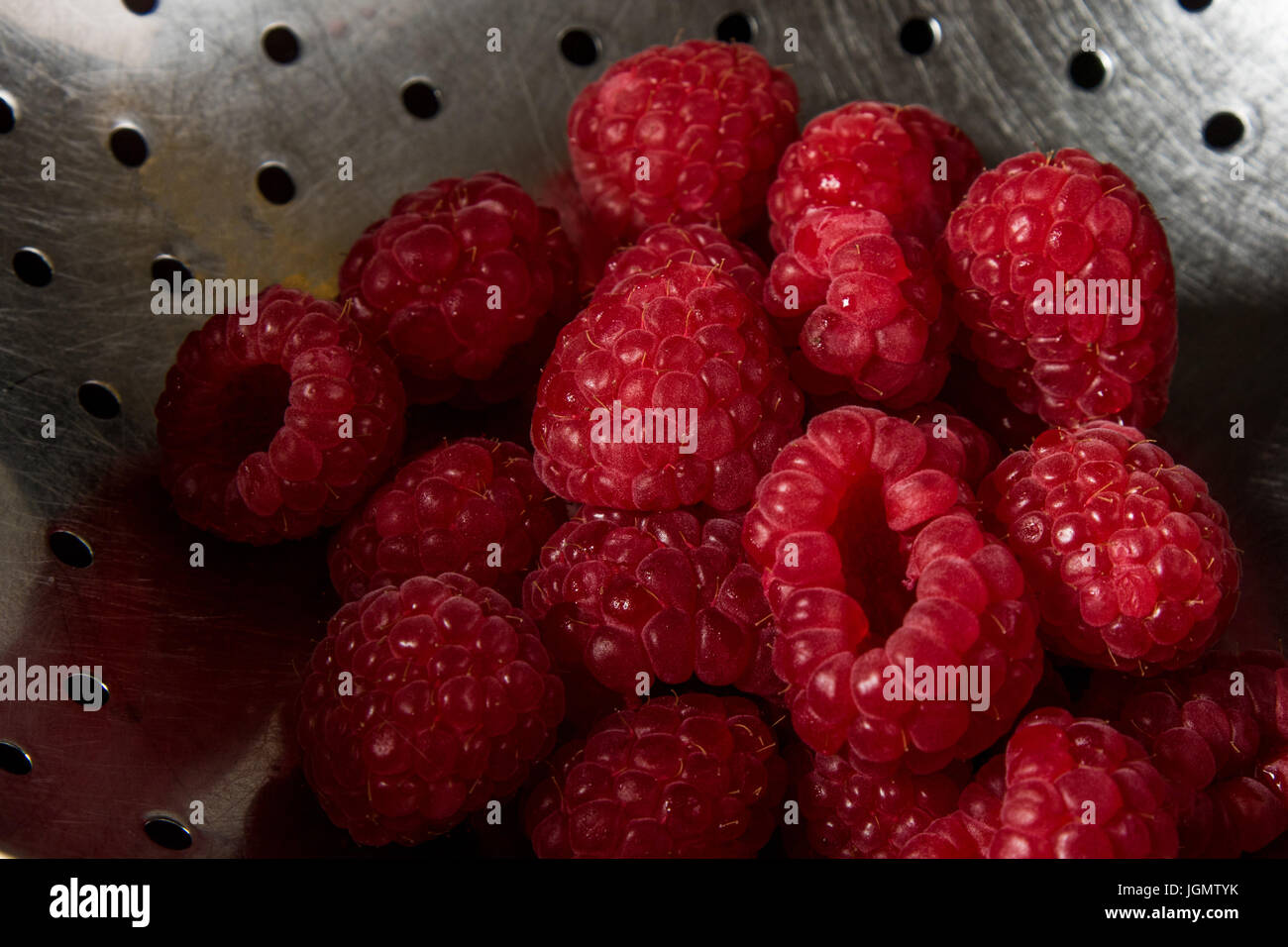 Raspberries in a colander isolated on a black background Stock Photo ...