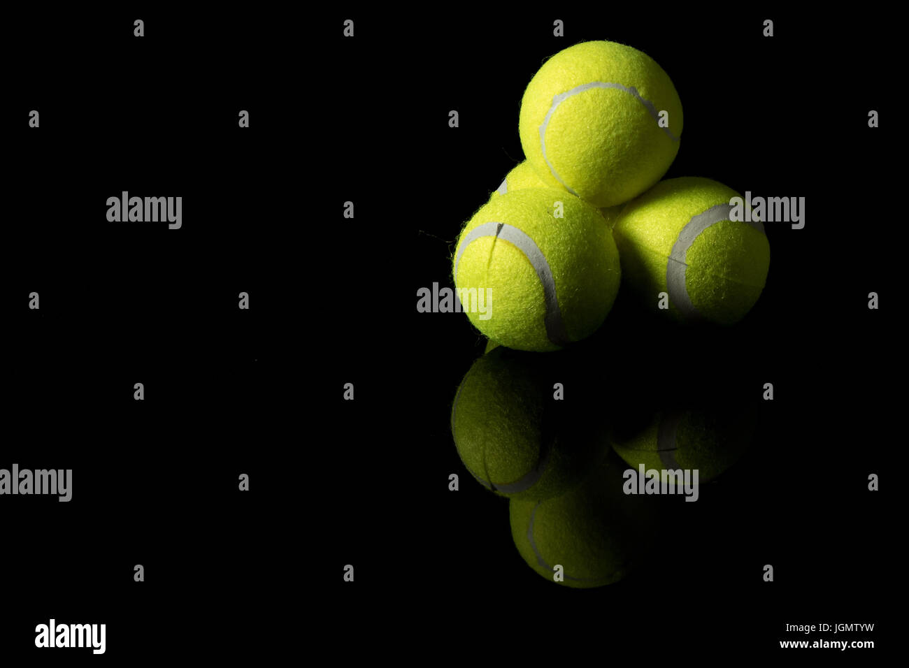 A stack of tennis balls isolated on a black background Stock Photo - Alamy