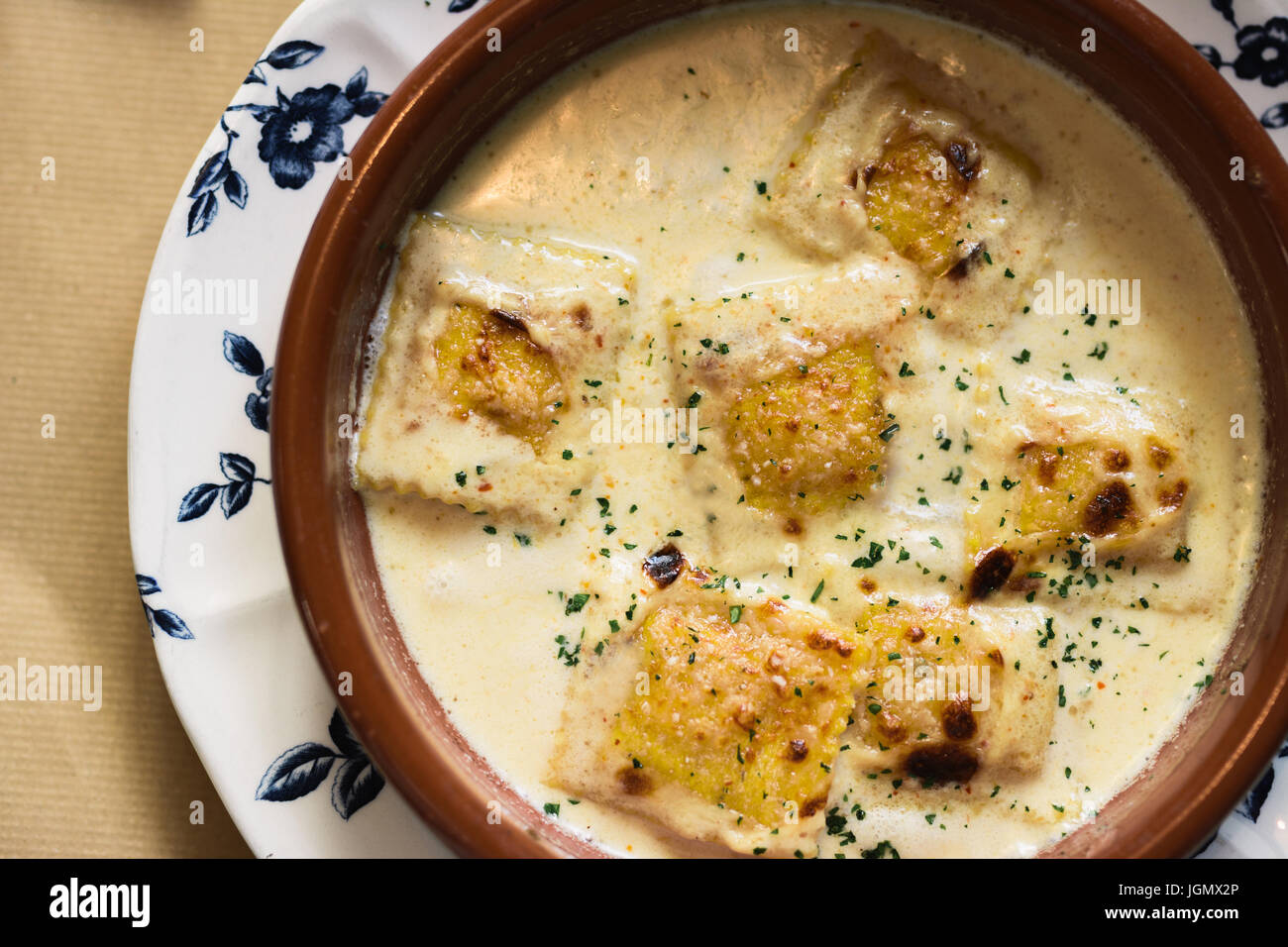 Person eating ravioli with gratin cheese, on the antique plate in ...