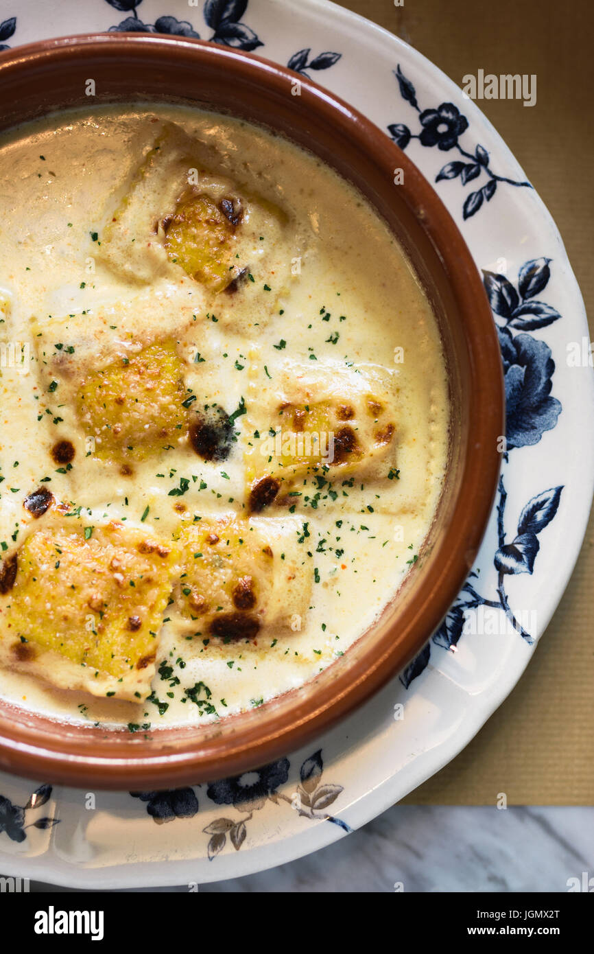 Person eating ravioli with gratin cheese, on the antique plate in ...