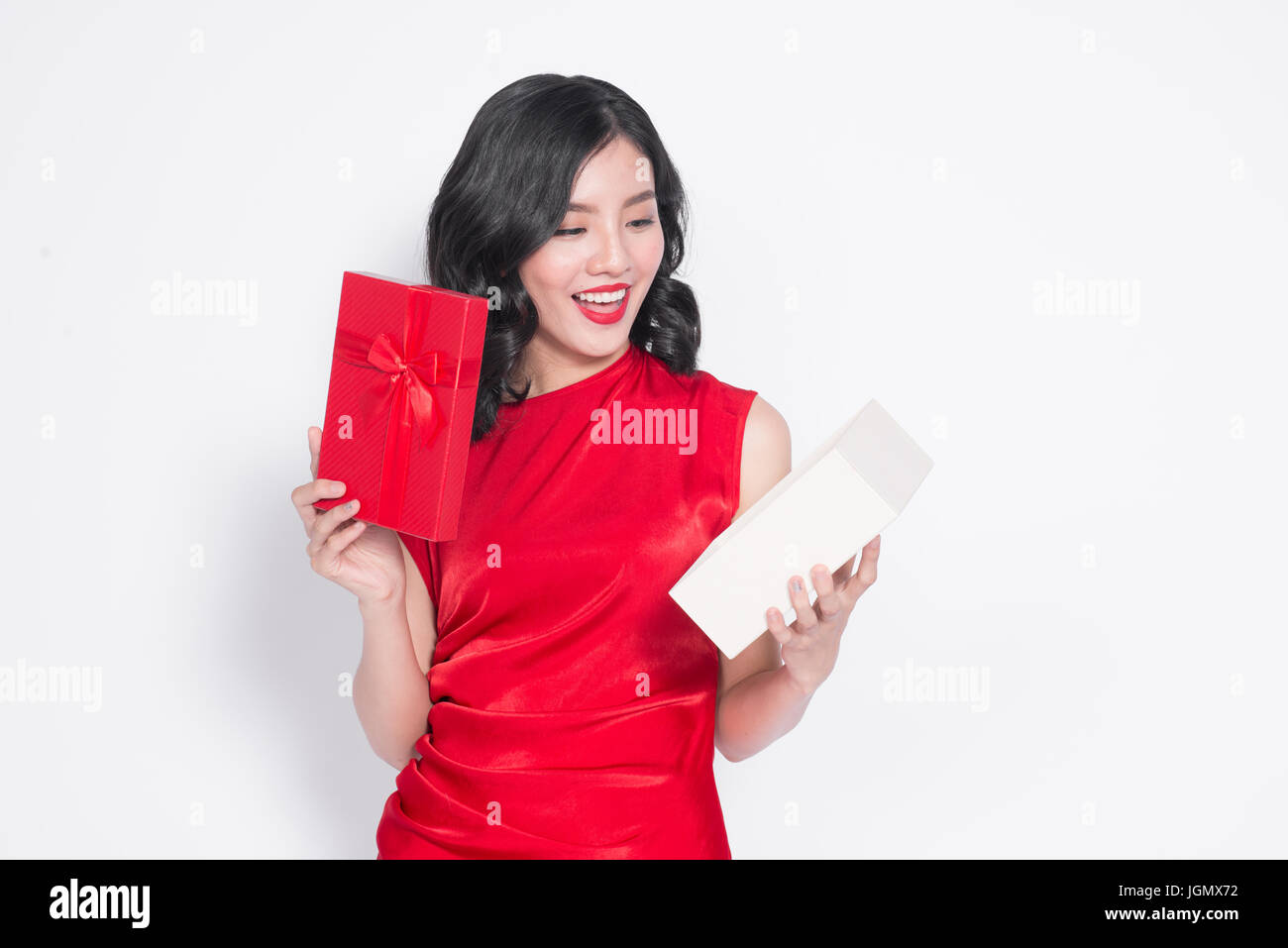 Pretty young glamorous asian woman dressed in red dress with a present ...
