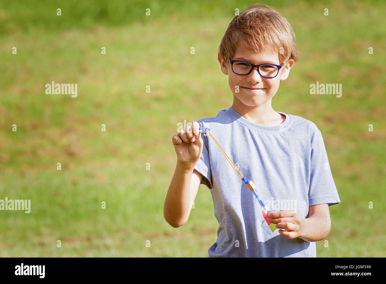 Child playing outdoors in a park with arrow helicopter elastic rocket ...
