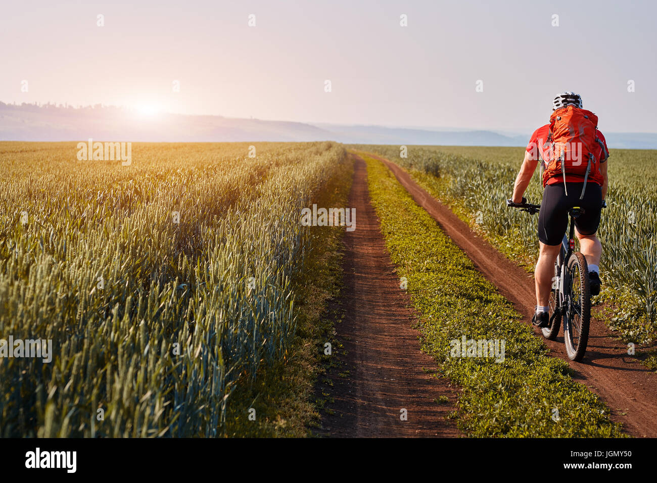 Rear view of the young cyclist riding mountainbike on the beautiful ...