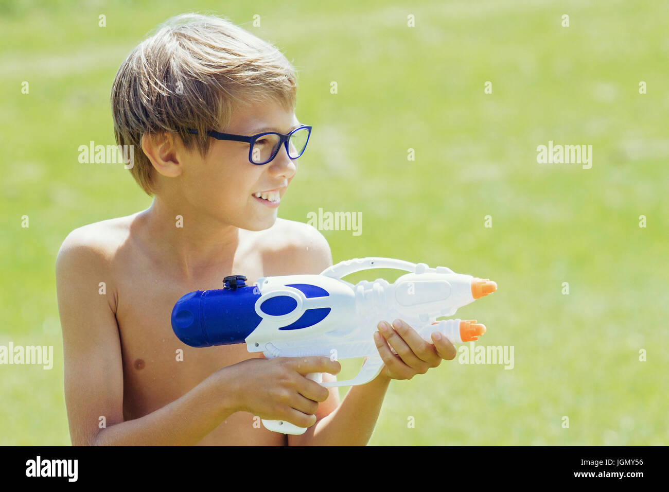 Smiling boy playing with water gun at hot summer day Stock Photo - Alamy