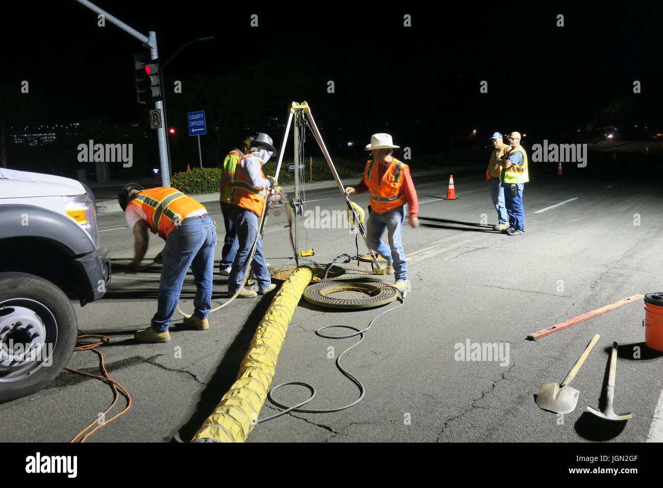 Men working on street sewer manhole at night Stock Photo - Alamy