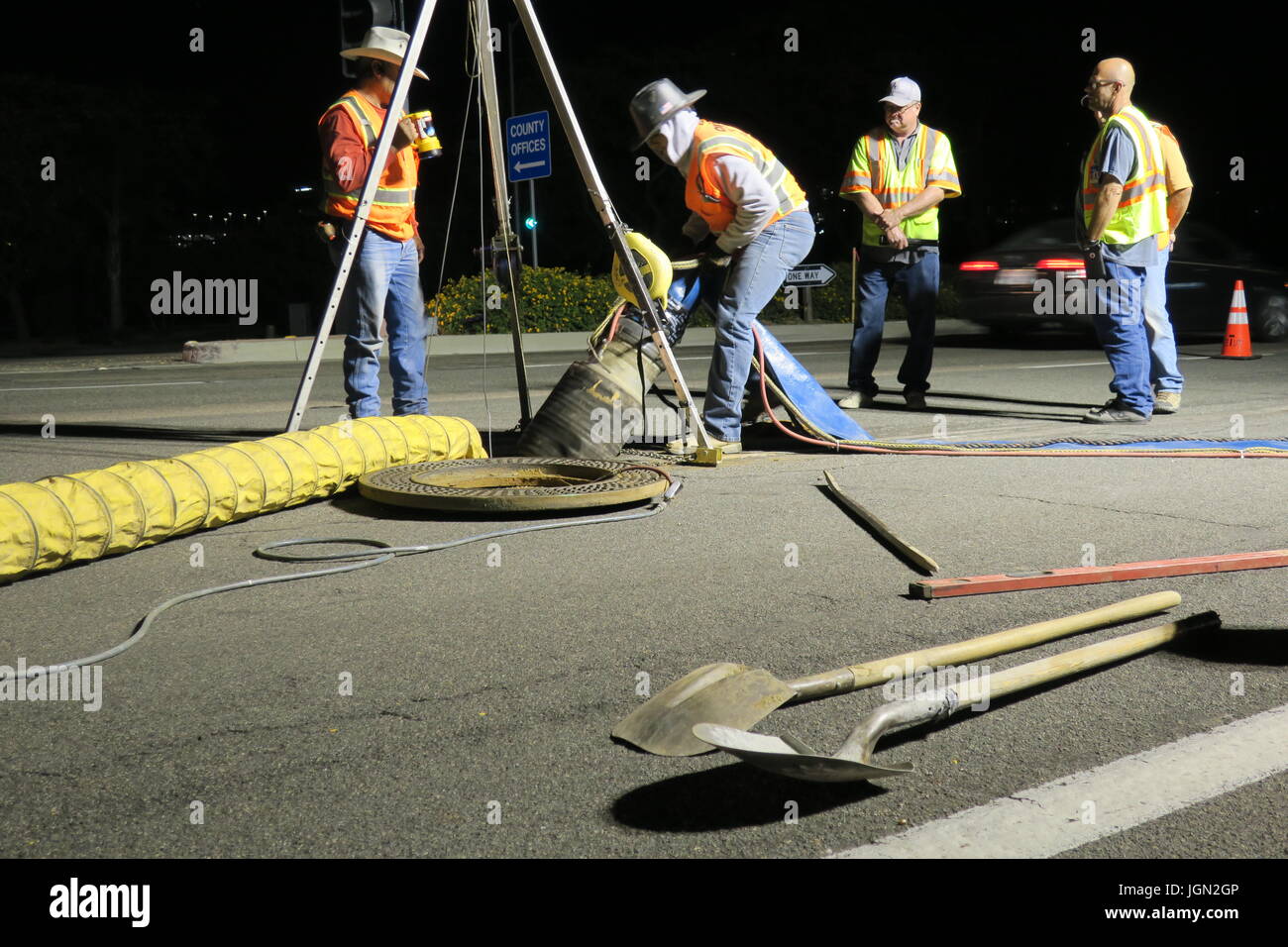 Men working on street sewer manhole at night Stock Photo - Alamy