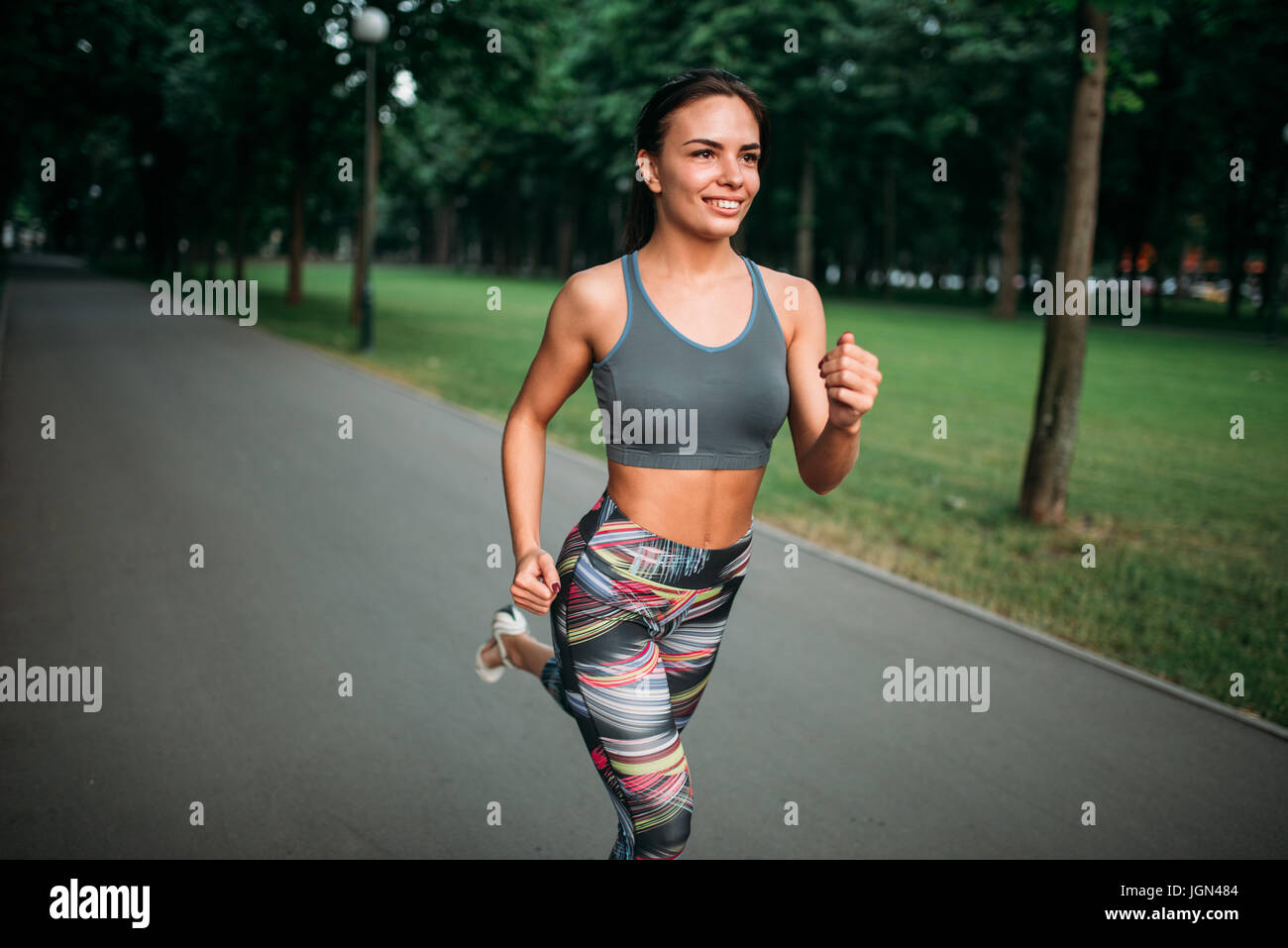 Slim woman jogging on sidewalk in summer park. Female runner on ...
