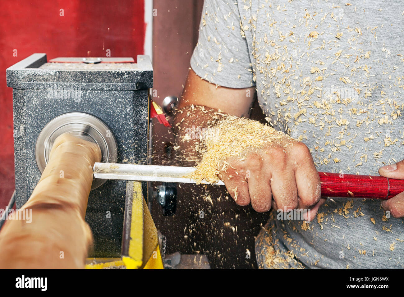 A close-up as a young man holds a chisel in his hand and makes a wooden ...