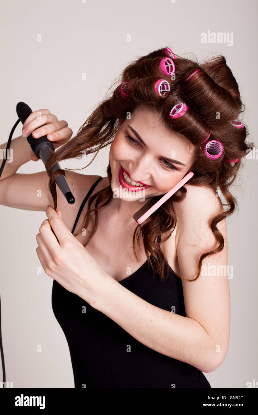 girl with hair curlers talking on the phone and makes the hairstyle ...