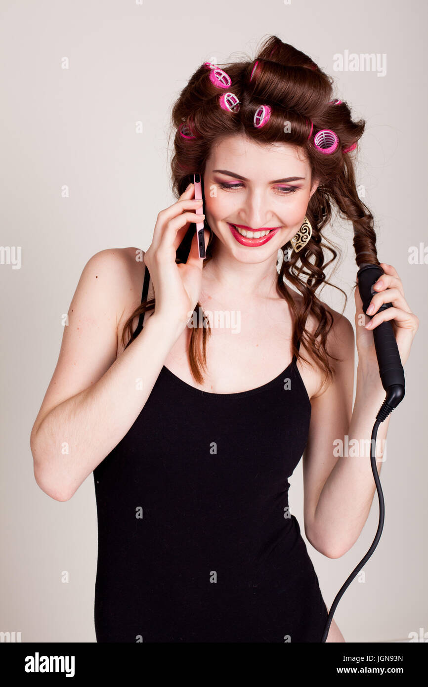 girl with hair curlers talking on the phone and makes the hairstyle ...