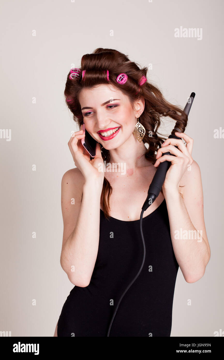 girl with hair curlers talking on the phone and makes the hairstyle ...