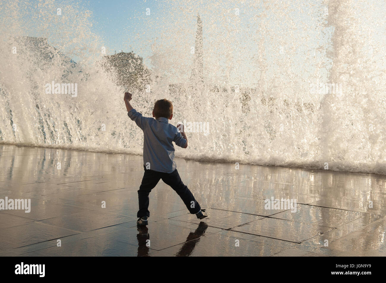 playful little kid playing with giant waves at ocean sunset Stock Photo ...