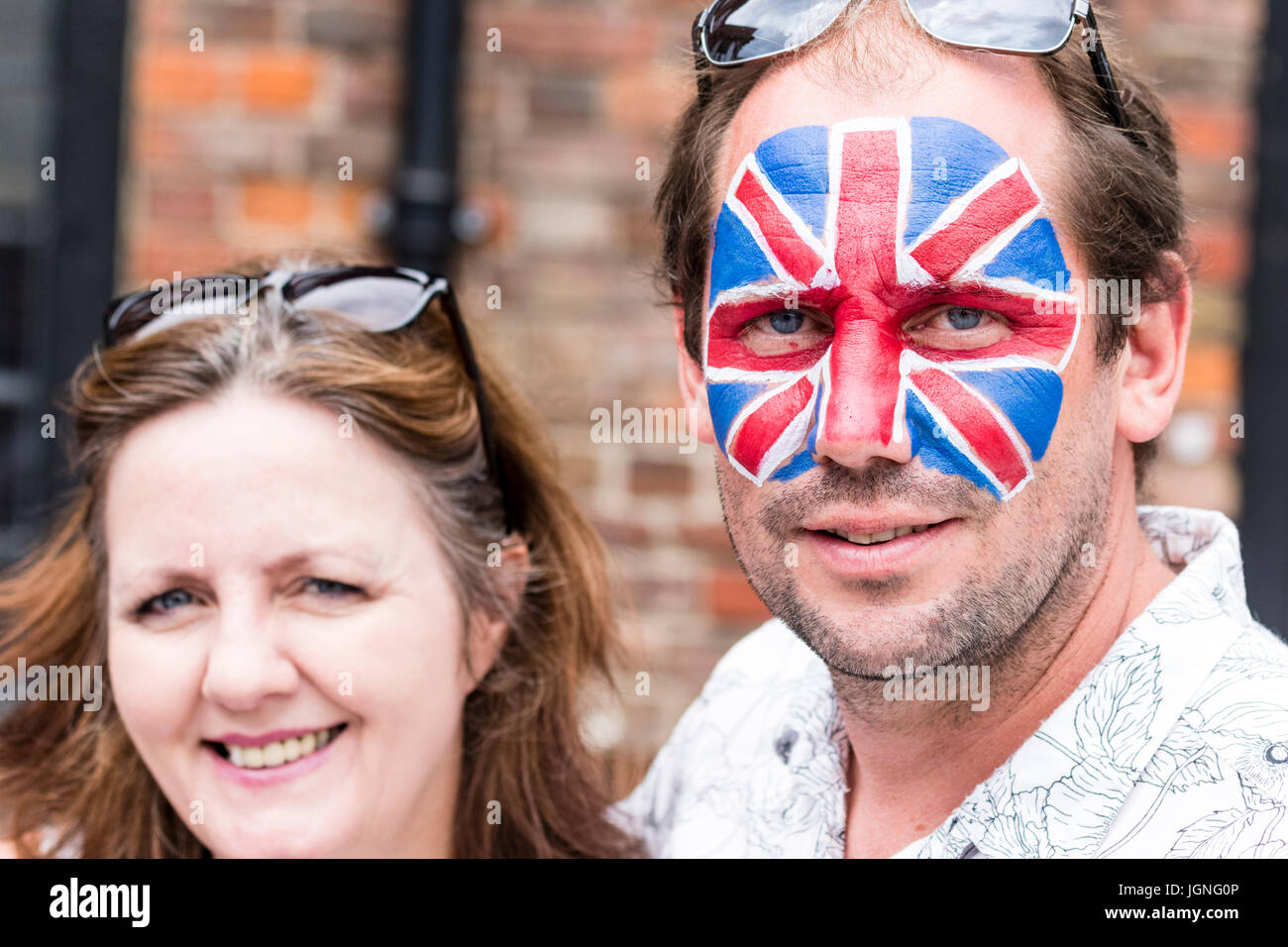 Caucasian couple, 30s, focus on man's face. Union jack painted on face ...