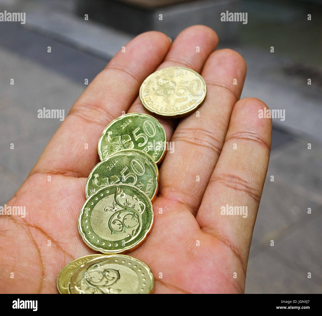 Golden Malaysian ringgit (MYR) coins in the hand Stock Photo - Alamy
