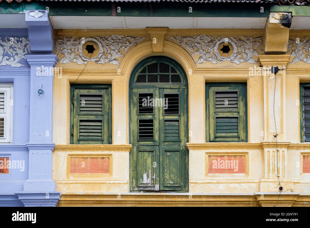 Louvered windows & stucco decorations on weathered façade of a ...