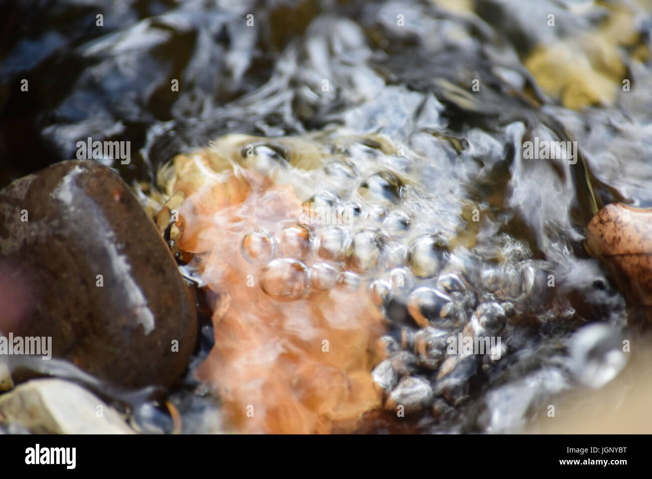 Bubbling water over pebbles Stock Photo - Alamy
