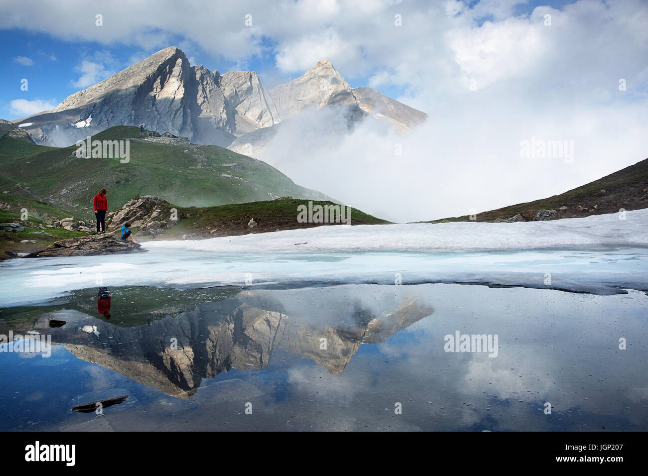 Mother and son by frozen alpine lake at col Agnel, on the border of ...