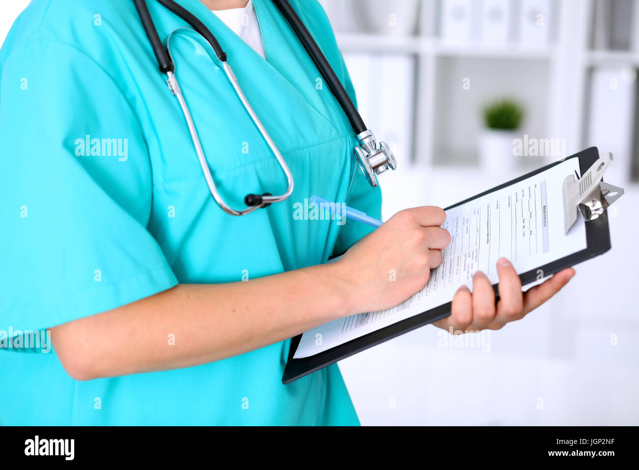 Close-up of a female doctor is filling out application form or medical ...