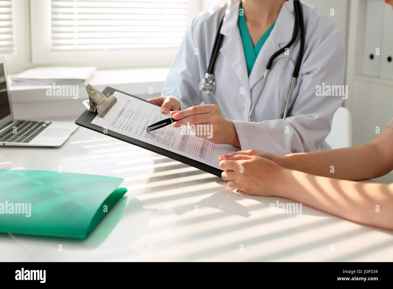 Doctor pointing into medical history form and discussing something with ...