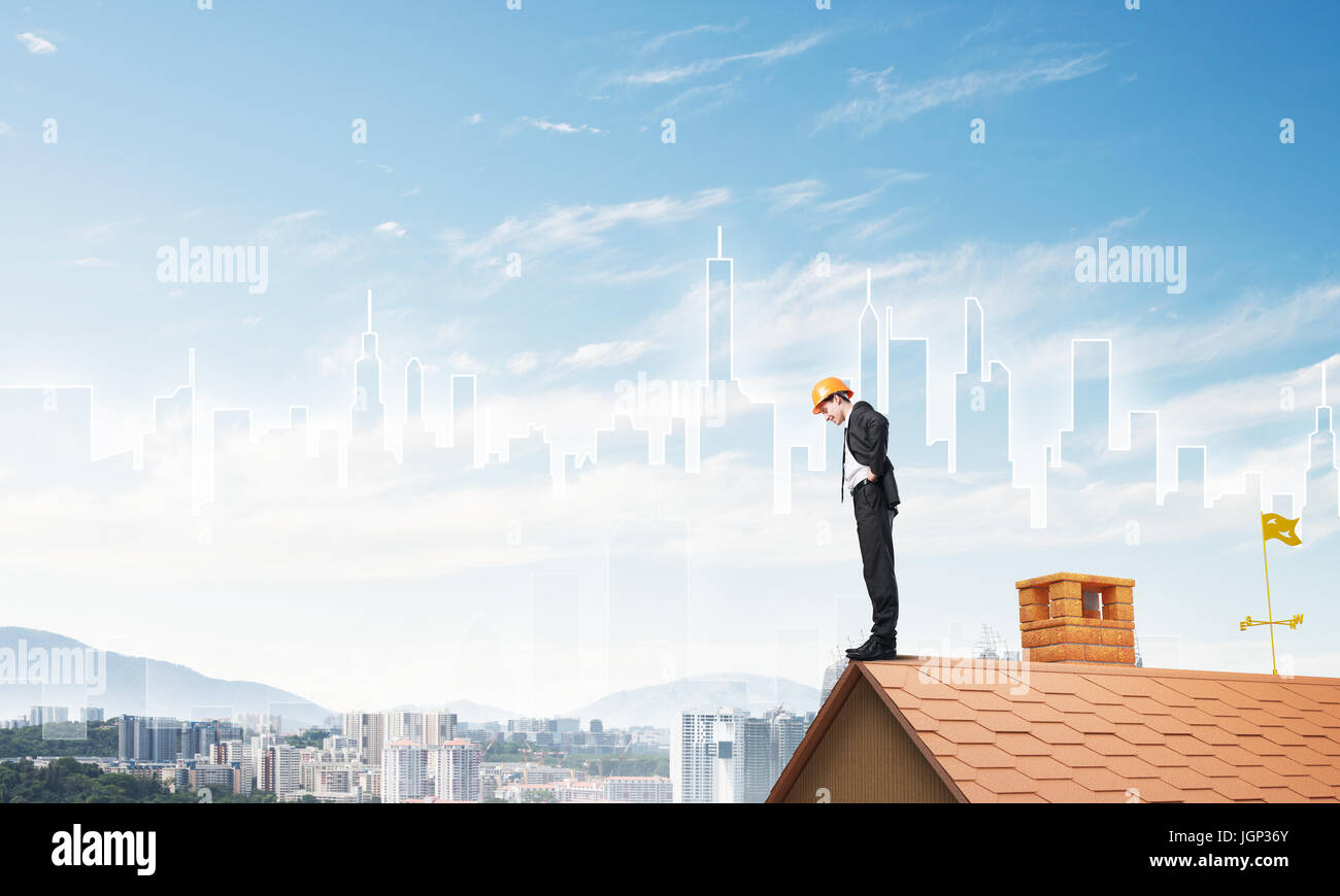 Engineer man standing on roof and looking down. Mixed media Stock Photo ...