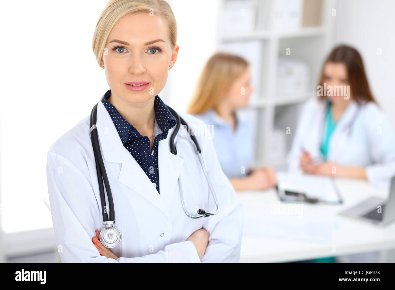 Female doctor smiling on the background with patient and his physician ...