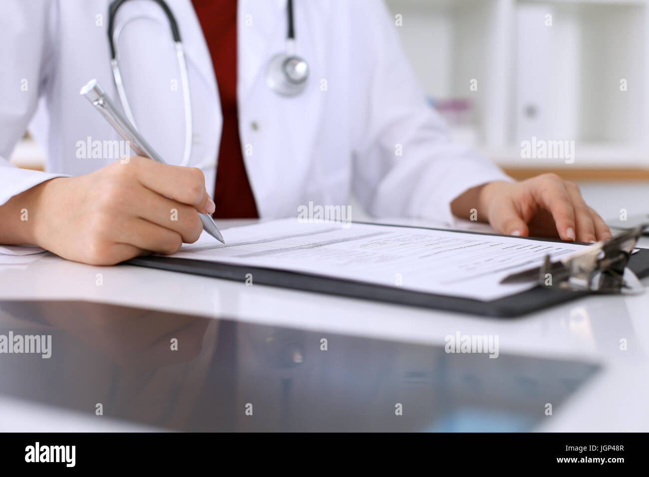 Close up of a female doctor filling up an application form while ...