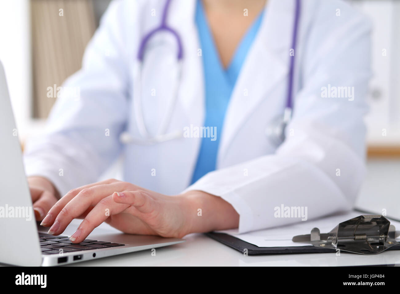 Close up of unknown female doctor typing on laptop computer while ...