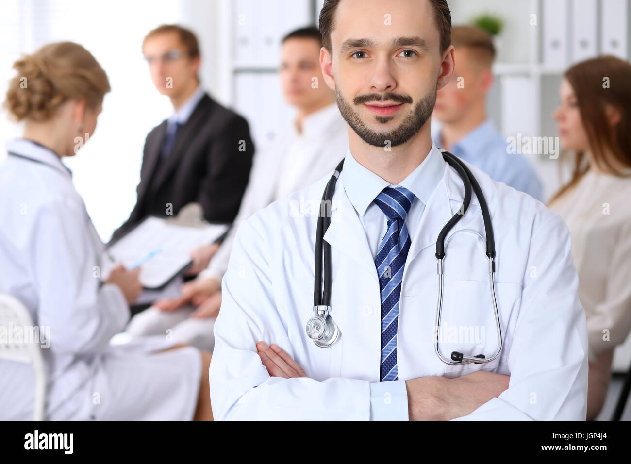 Friendly male doctor on the background doctor and many patients Stock ...