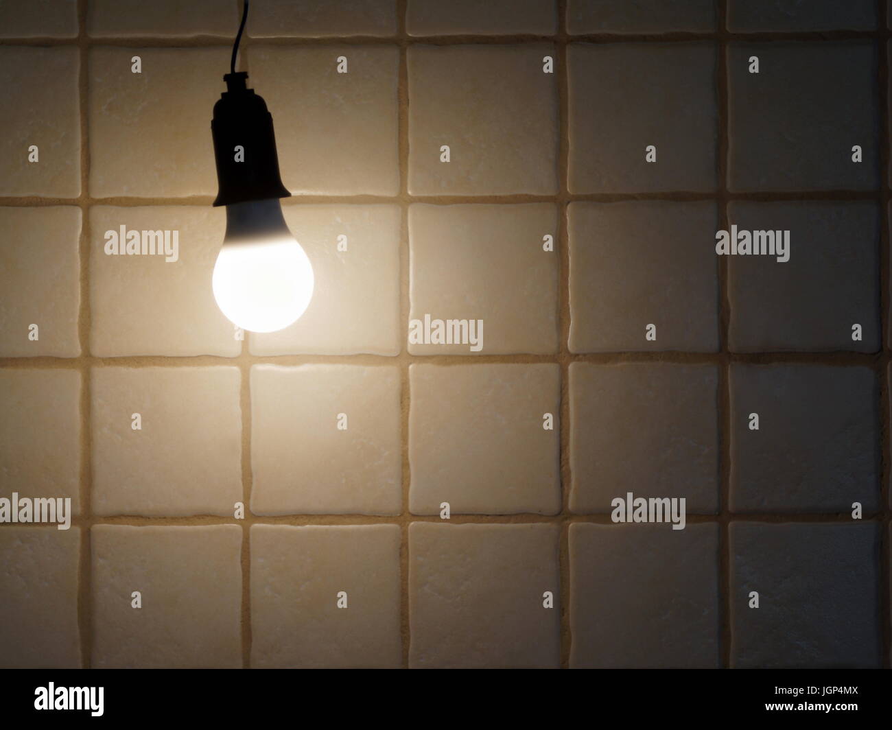 A lighted bulb on the background of a wall tiled. LED Light Stock Photo ...