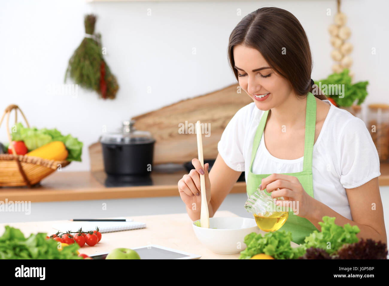 Beautiful Hispanic woman is cooking in the kitchen. Housewife is ...