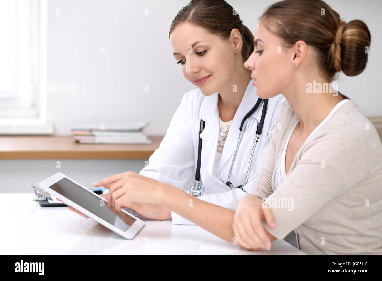 Doctor and patient sitting at the desk. Physician pointing into laptop ...