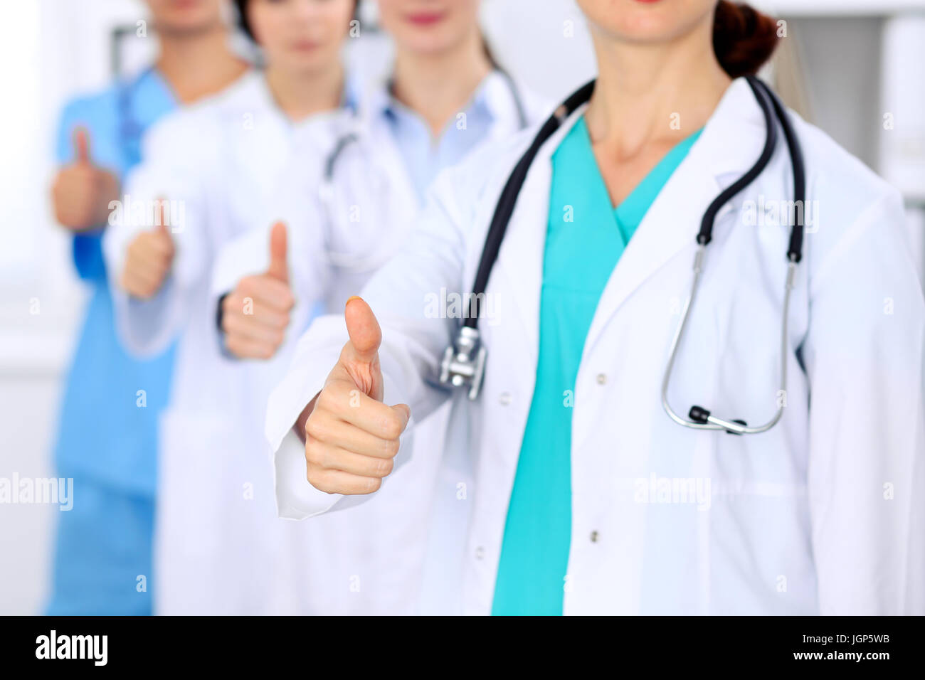 Group of doctors showing OK or approval sign with thumb up. High level ...