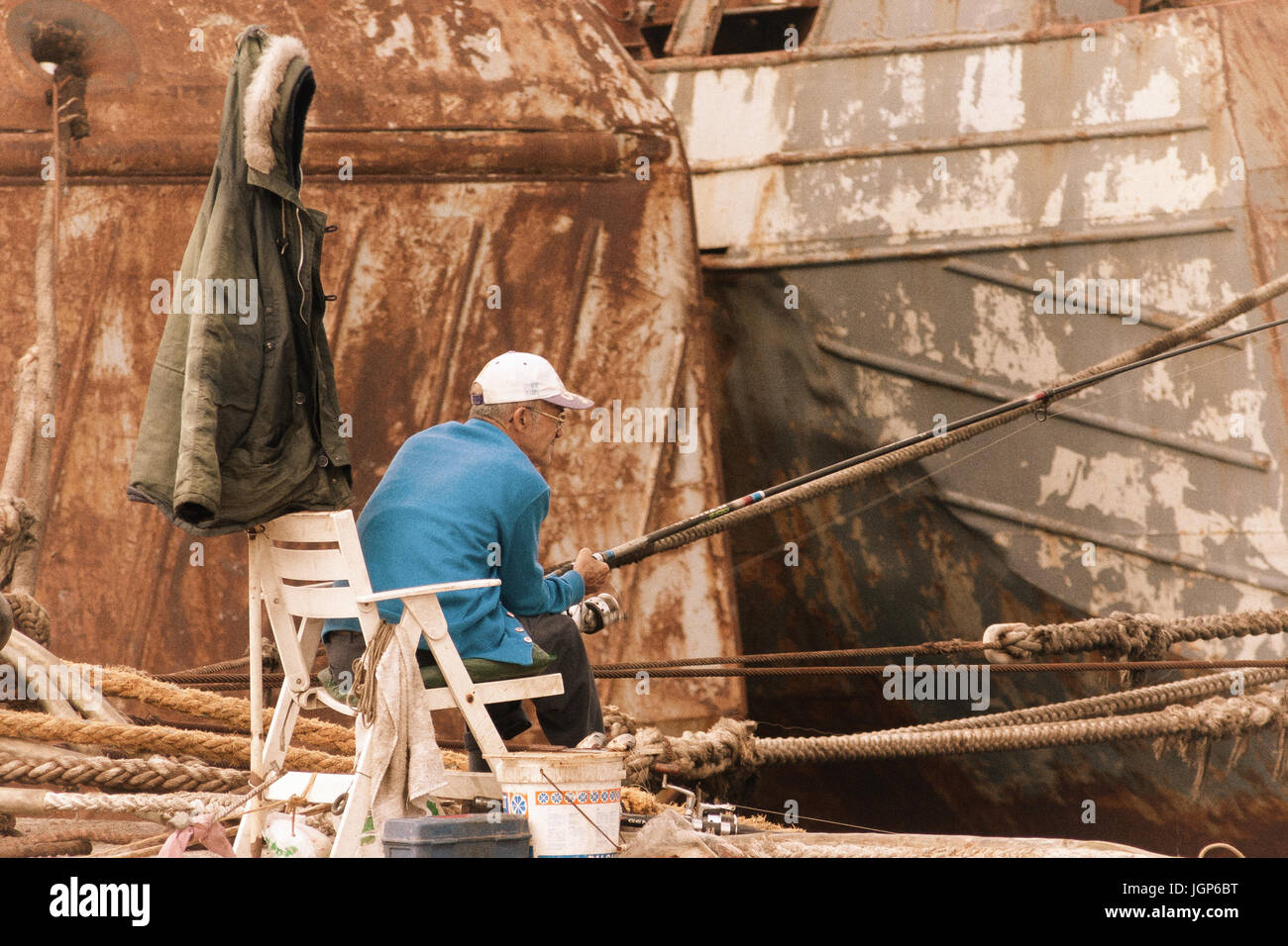 Elderly man fishing near rusting trawlers in Spanish port Stock Photo ...