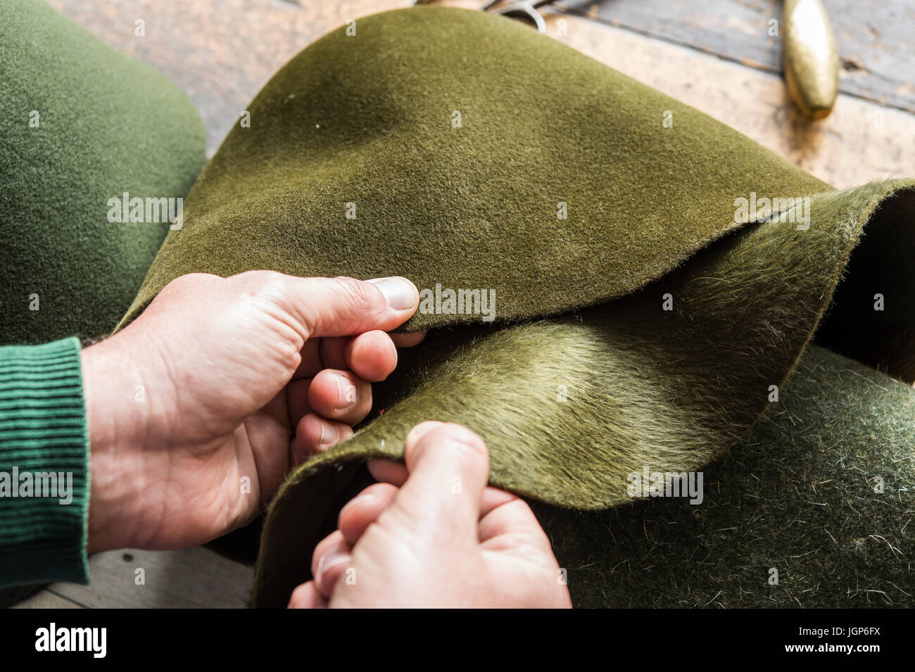 Hands checking different wool felt hat bodies, shades of green, on ...