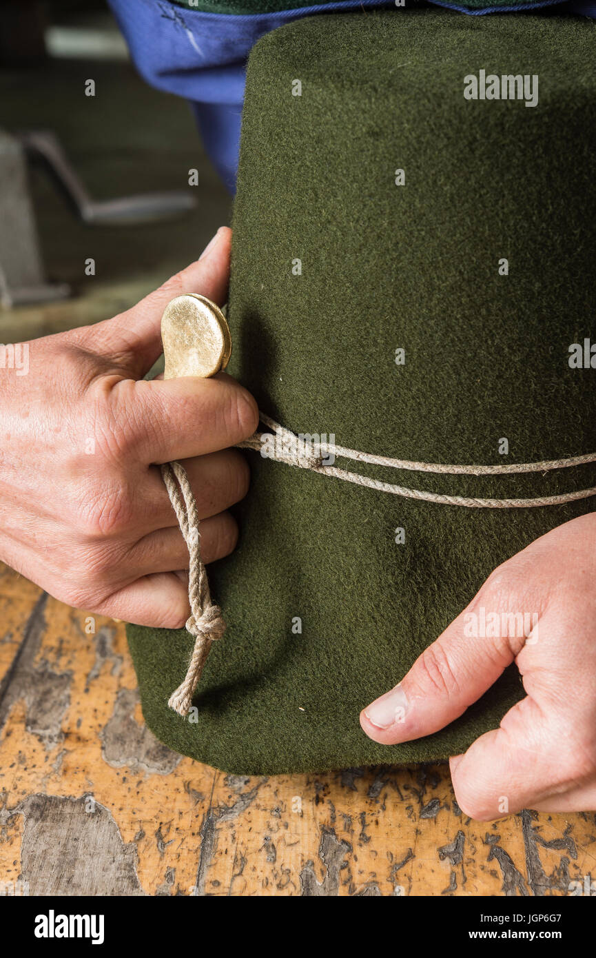 Tightening the shaping cord around a wool felt hat, using iron tool ...