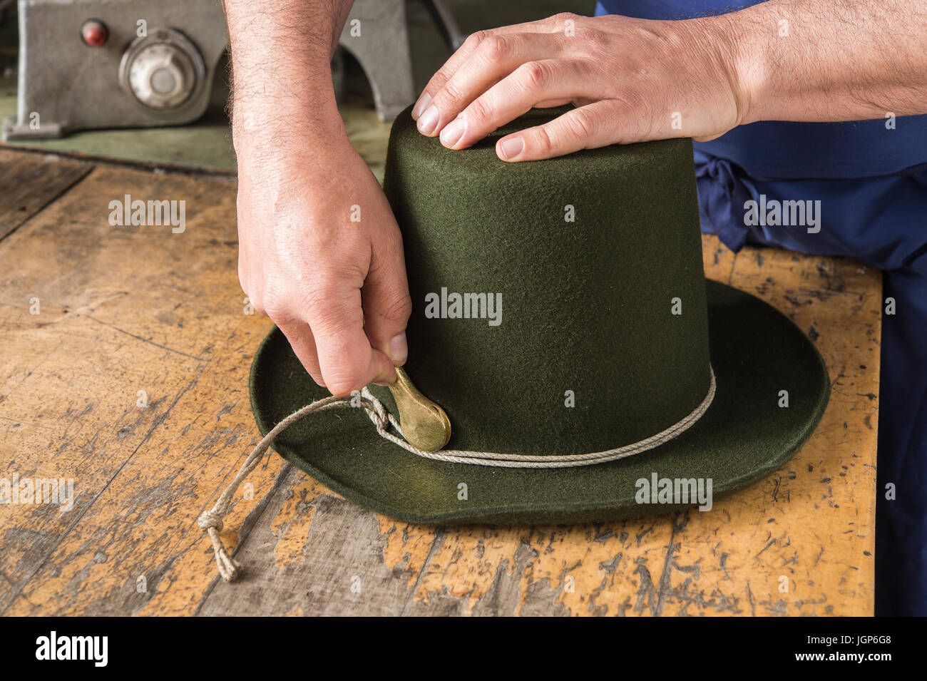 Tightening the shaping cord around a wool felt hat, using iron tool ...