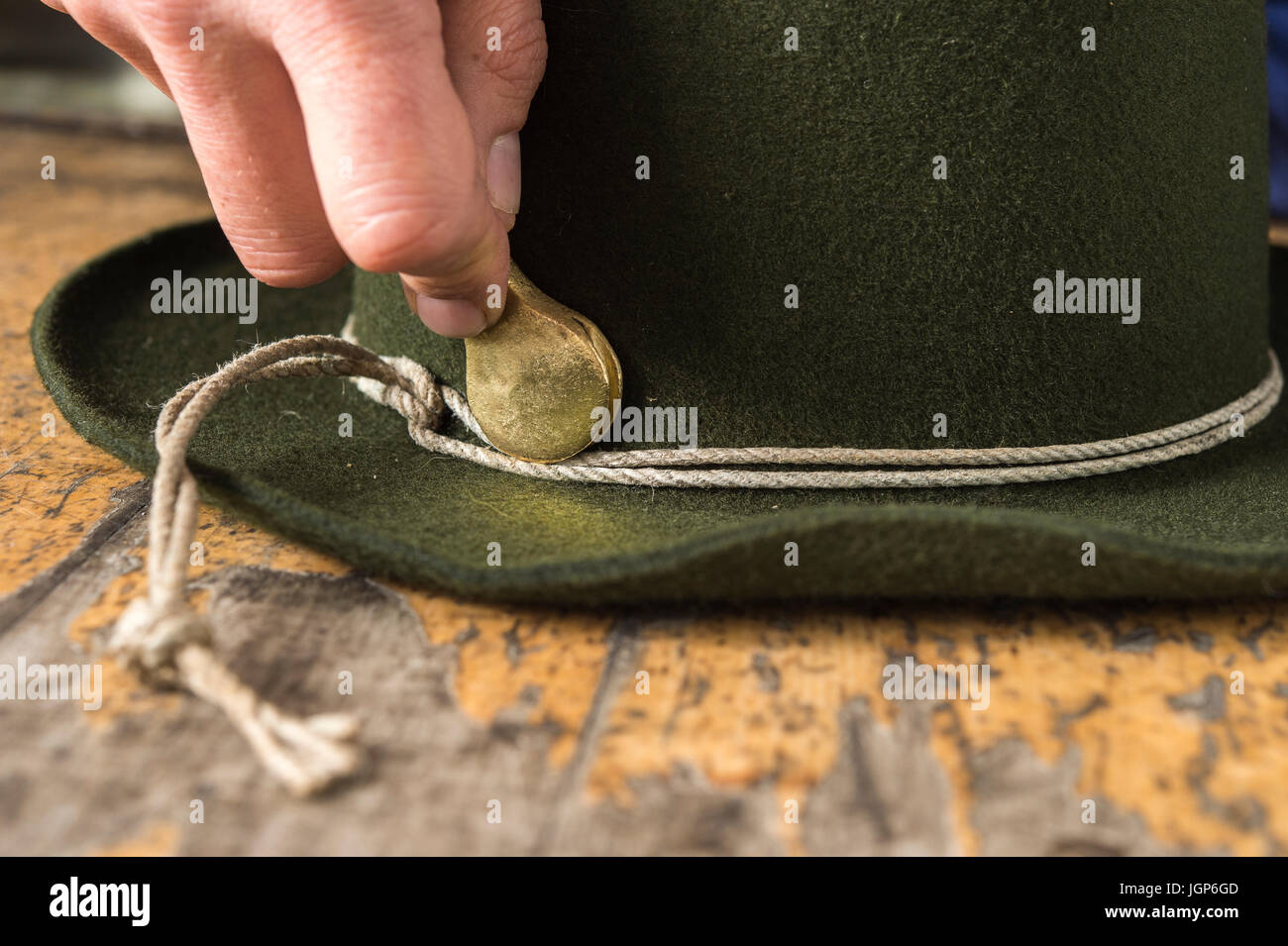 Tightening the shaping cord around a wool felt hat, using iron tool ...
