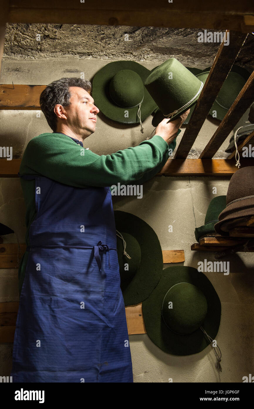 Hatter placing wool felt hat with shaping cord to dry on wooden boards ...