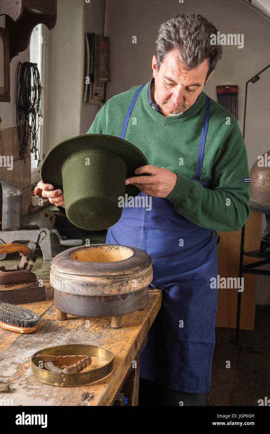Hatter holding dry wool felt hat over an edge mold, hatmaker workshop ...