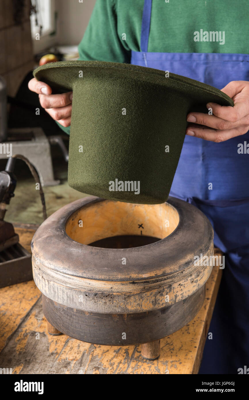 Hands holding dry wool felt hat over an edge mold, hatmaker workshop ...