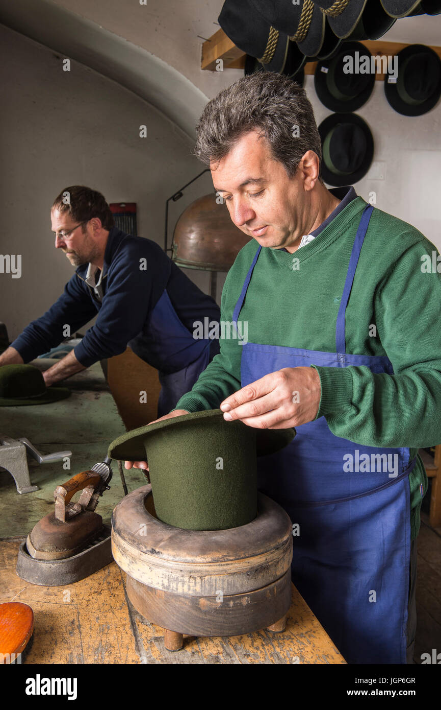 Hatter holding dry wool felt hat in an edge mold, hatmaker workshop ...