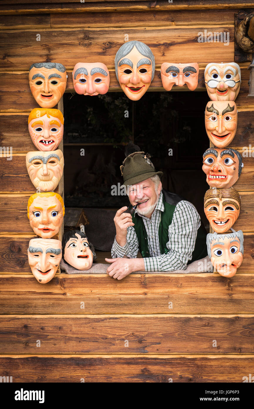 Wooden mask carver in a window, framed by painted wooden masks, wooden ...