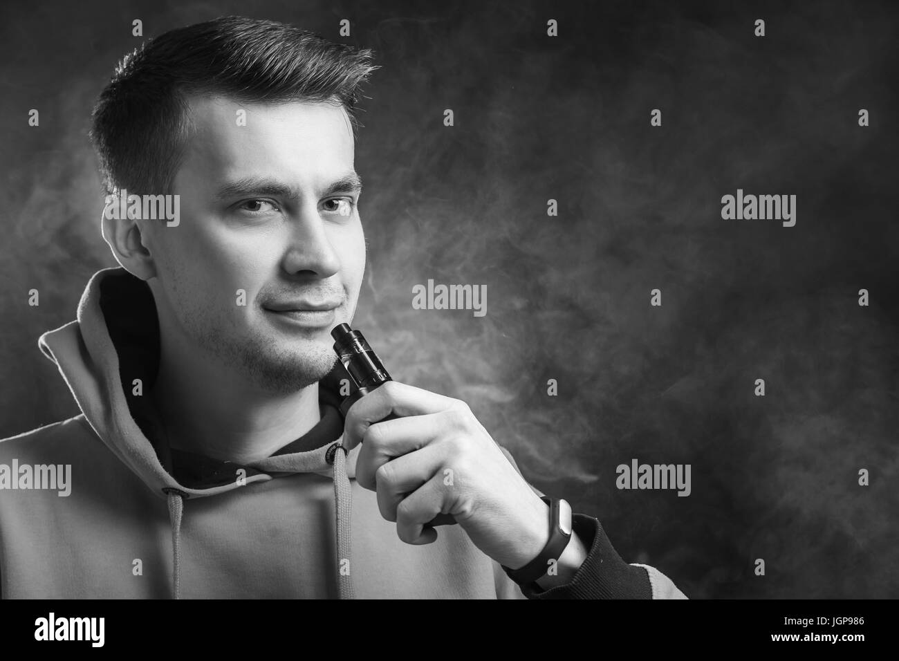 Vape. Young handsome white guy is admiting puffs of steam from the ...