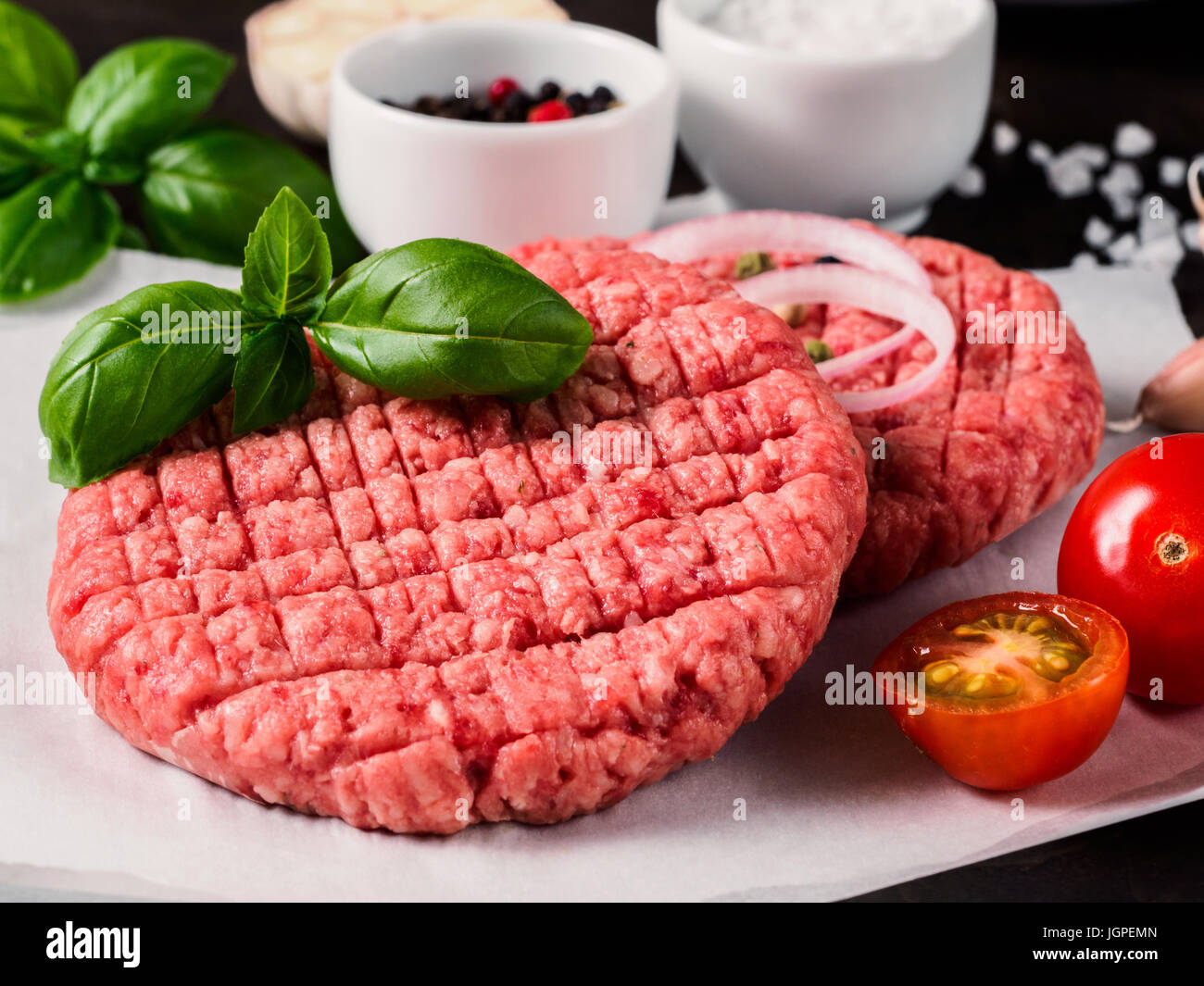 Close up view of two raw meat steak cutlets for burger with vegetables ...
