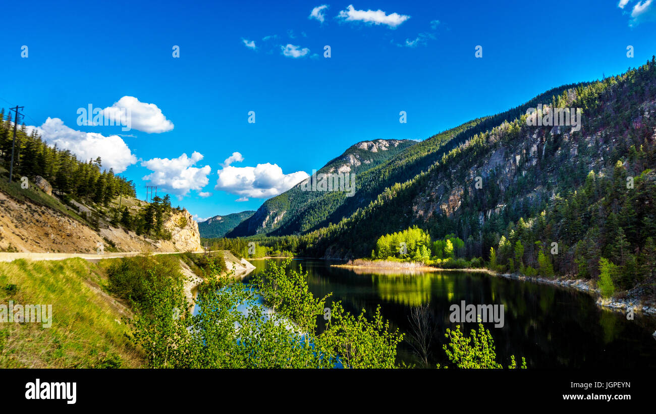 Blue sky, trees and mountains reflecting in the smooth surface on the ...