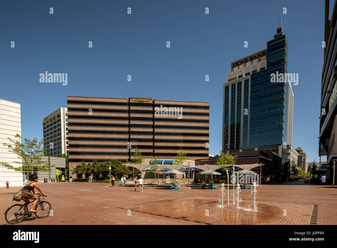 Pleasant square meeting place in downtown with a lady riding a bike ...