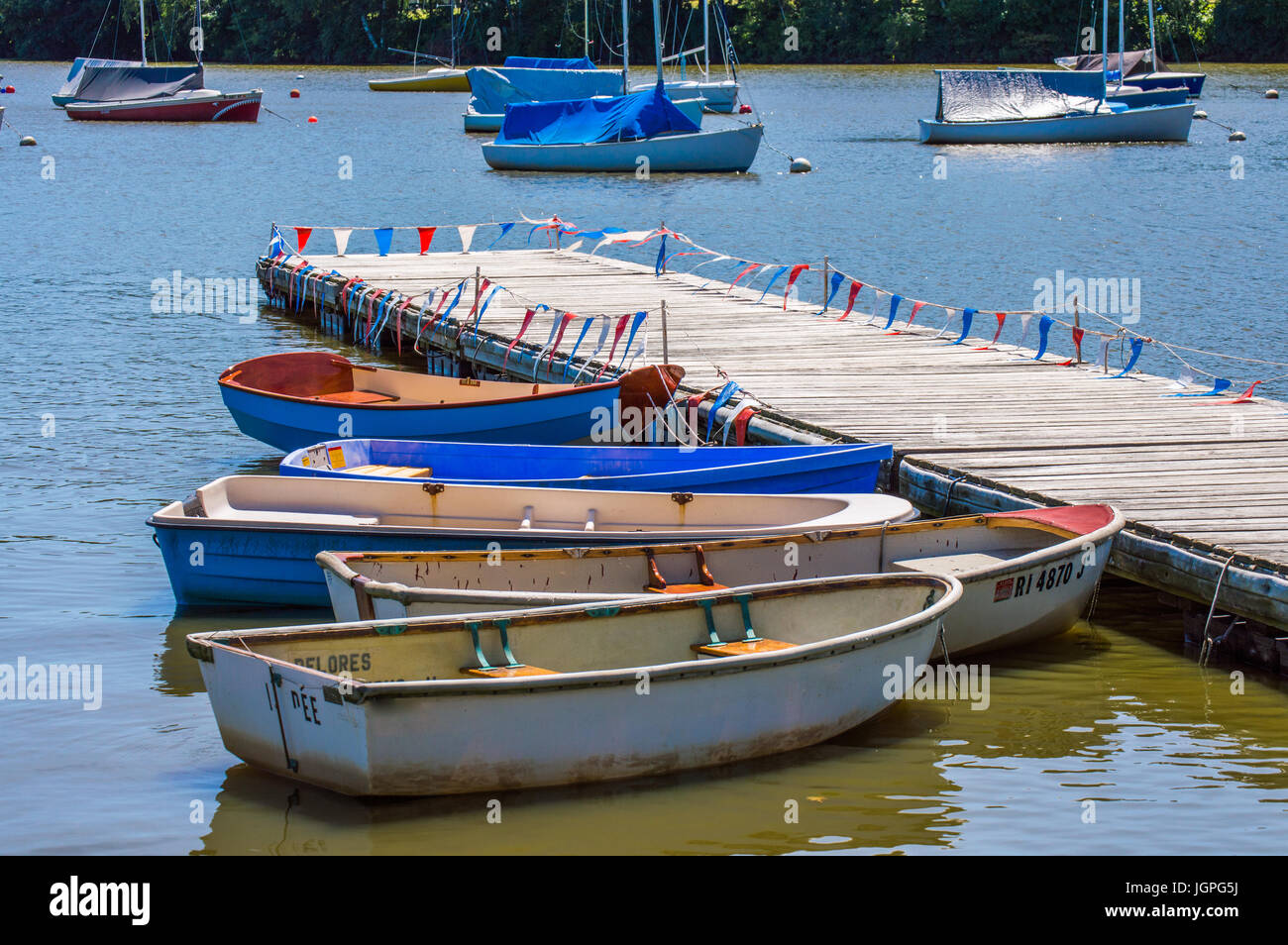 5 row boats tied to weathered wooden dock with sailboats in the ...