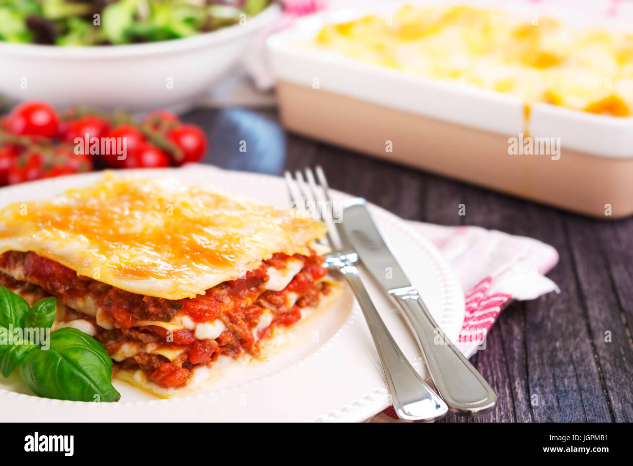 A portion of homemade lasagna on a plate on a brightly lit table Stock ...